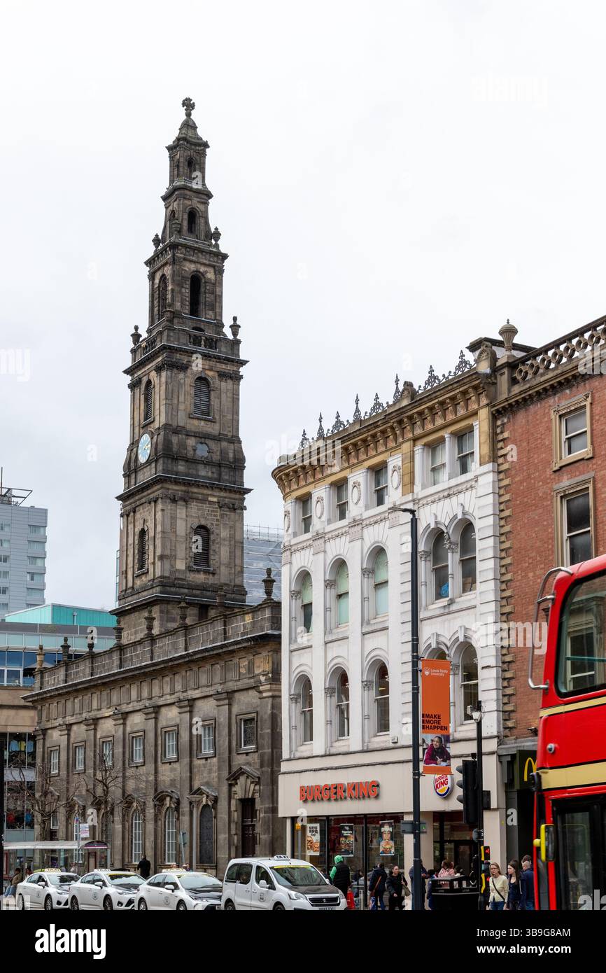 Urban scene with a tall church tower, adjacent buildings, pedestrians ...