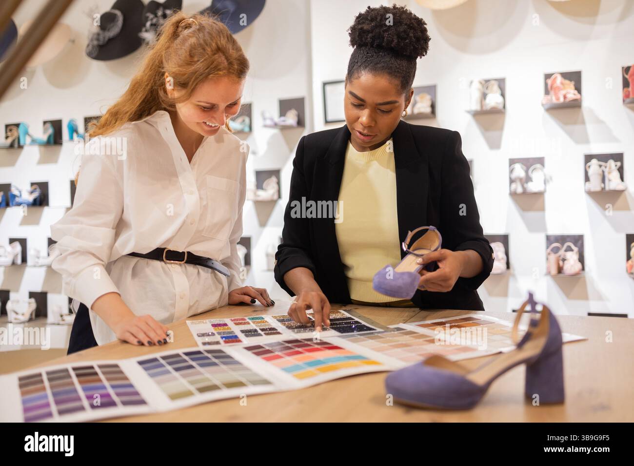 Two women discuss color options for footwear in a bridal studio. They ...