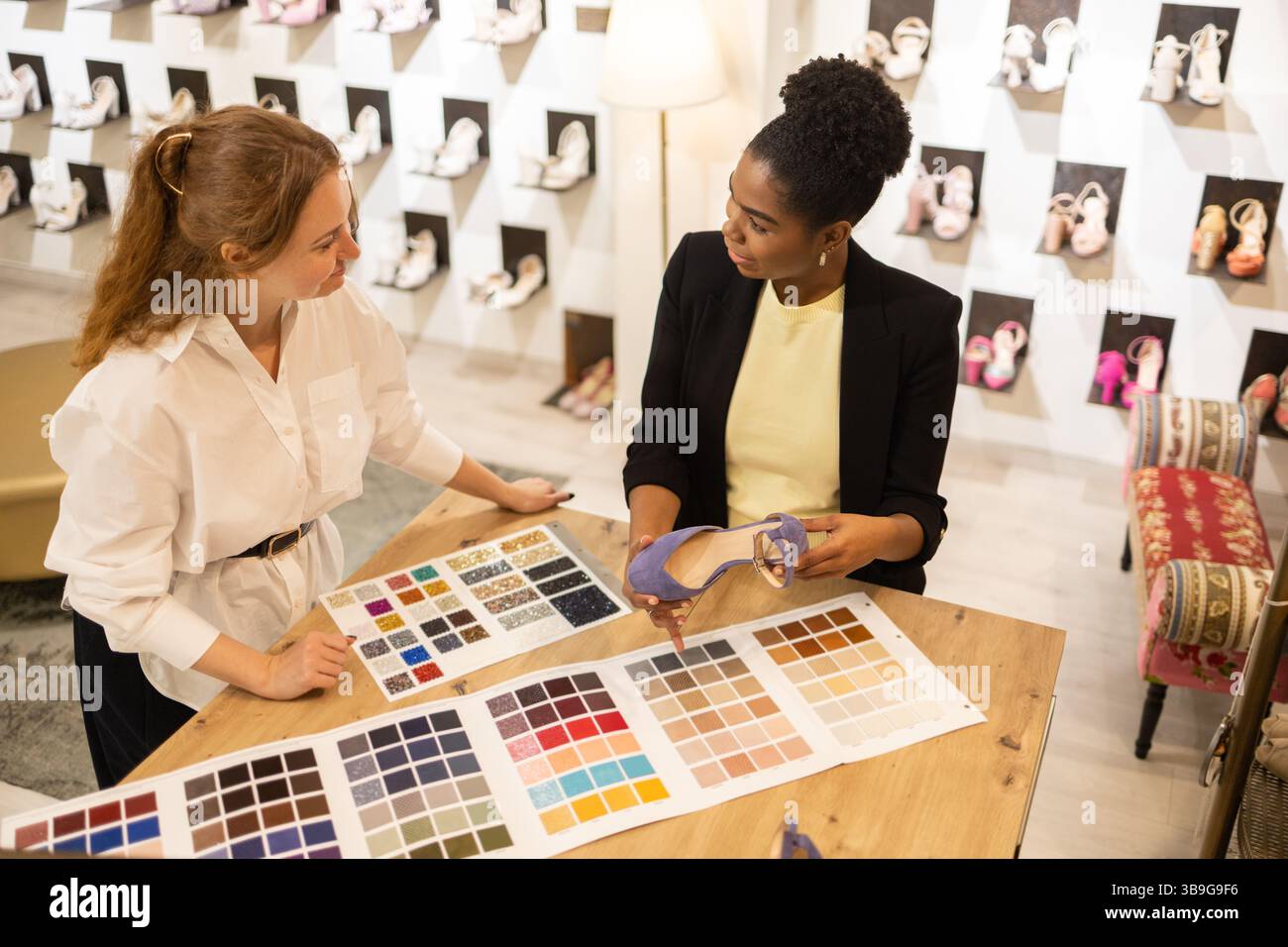 Two women collaborate over color swatches and shoe selection in a ...