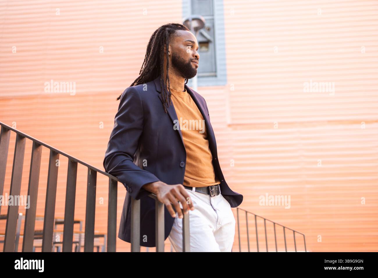 A cuban business man stands by a railing against a modern, orange ...