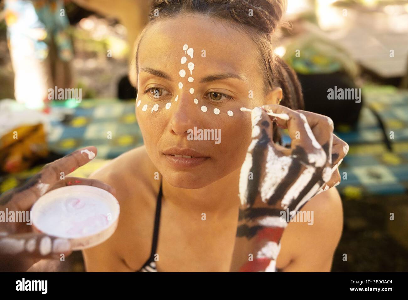 A tourist gets traditional face painting on Waigeo Island, Indonesia ...