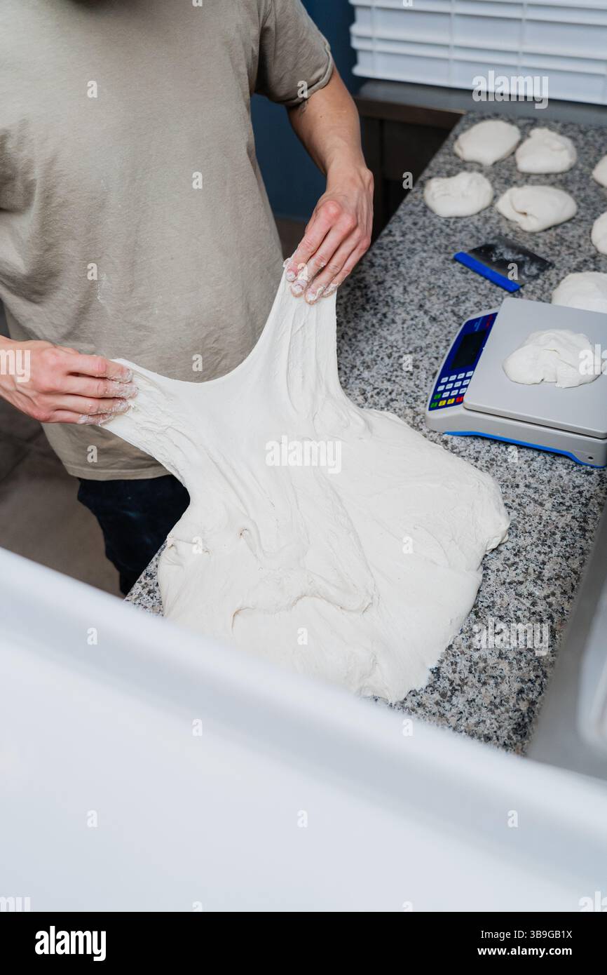 A person skillfully stretches and prepares pizza dough on a granite ...