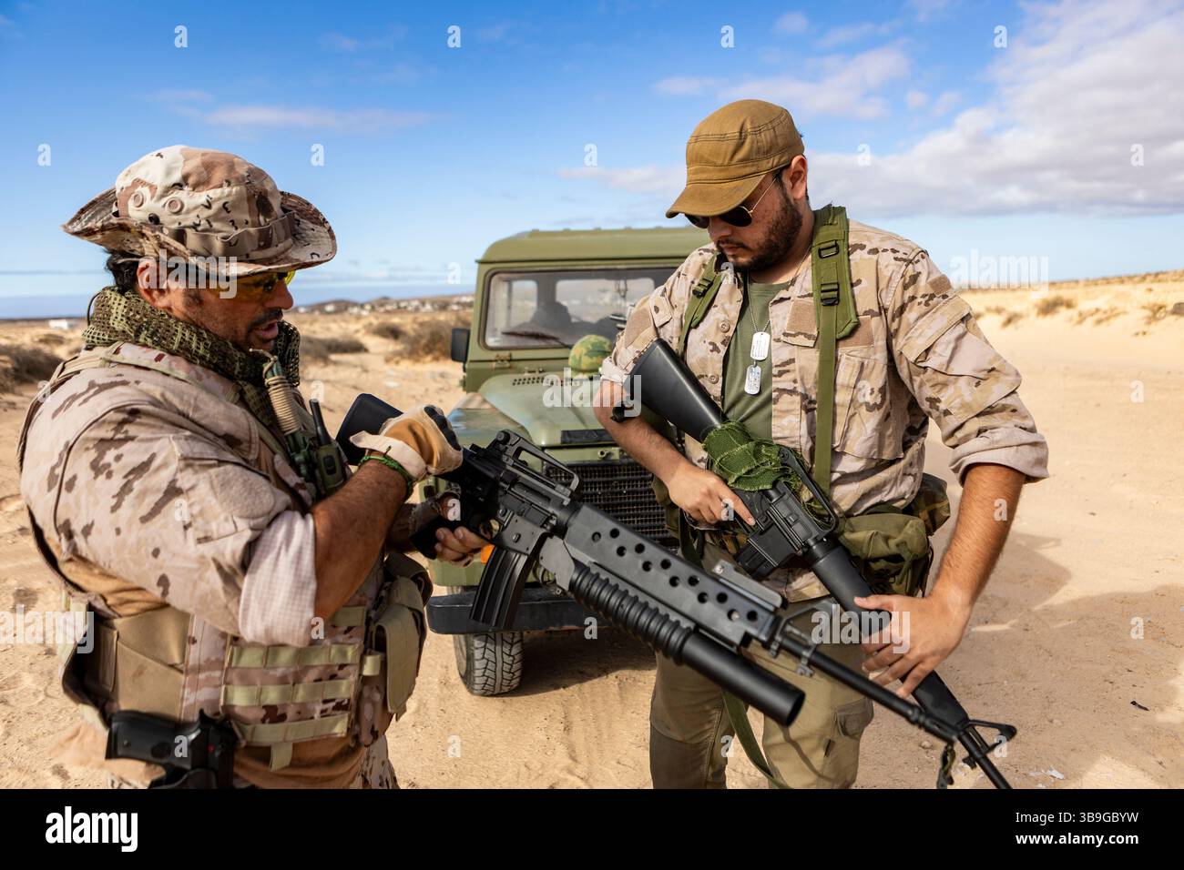 Two soldiers in desert gear, equipped with rifles, prepare for a ...