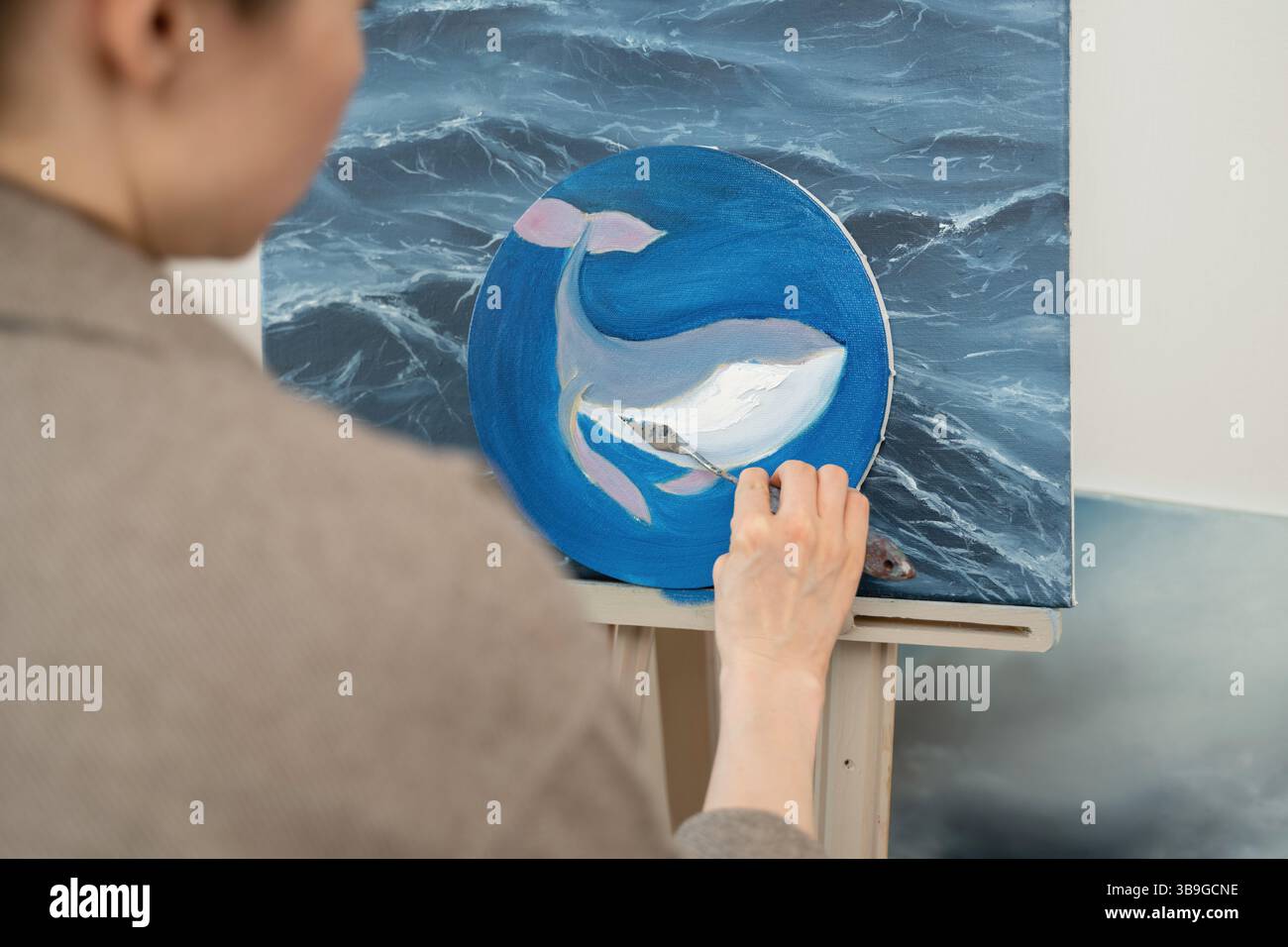 An artist skillfully paints a whale on a small round canvas, drawing ...