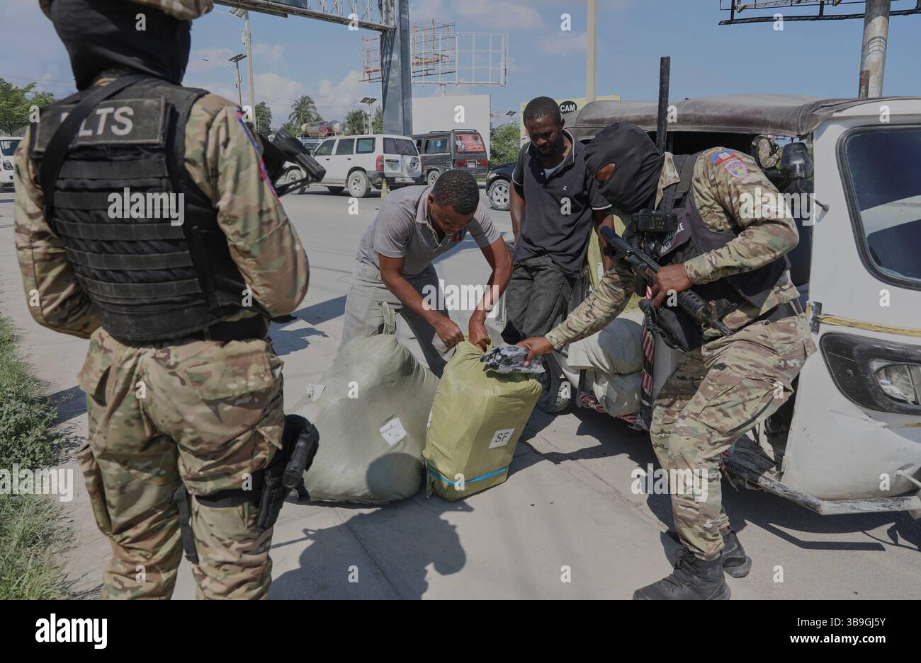 Police inspect goods being transported by a man stopped at a checkpoint ...