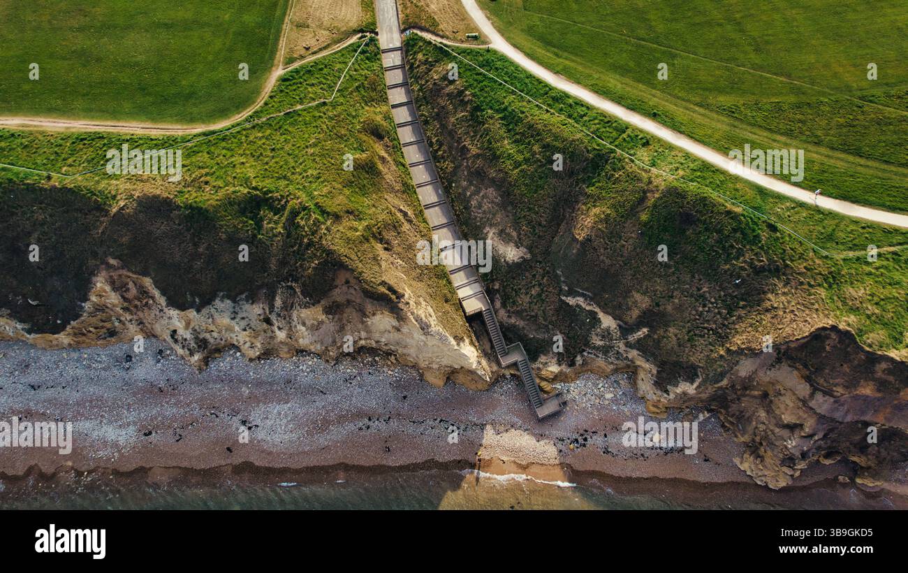 Aerial view of a cliffside with a path, stairs leading to a pebble ...