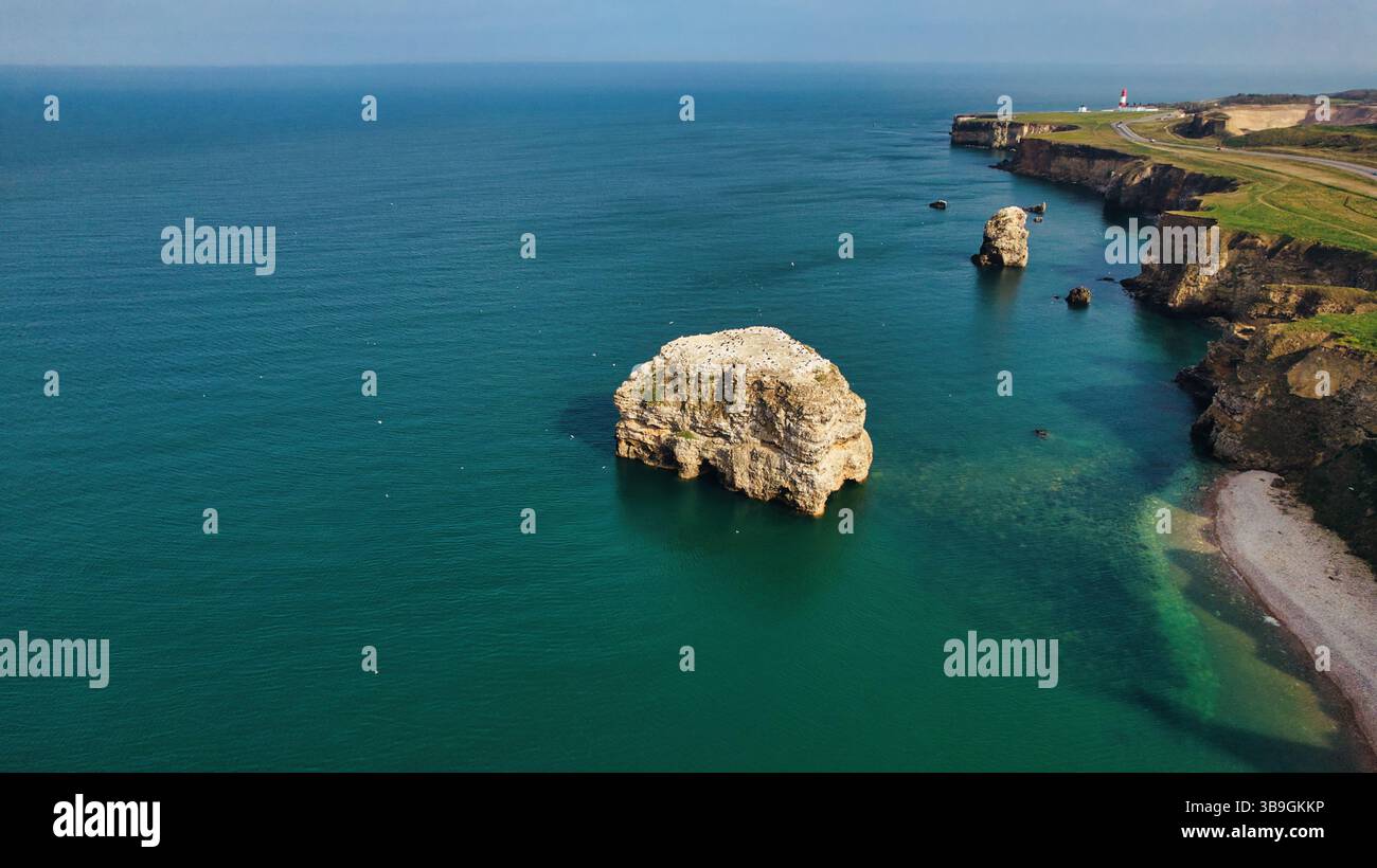 Aerial view of rocky cliffs and sea stacks along a coastline. Turquoise ...