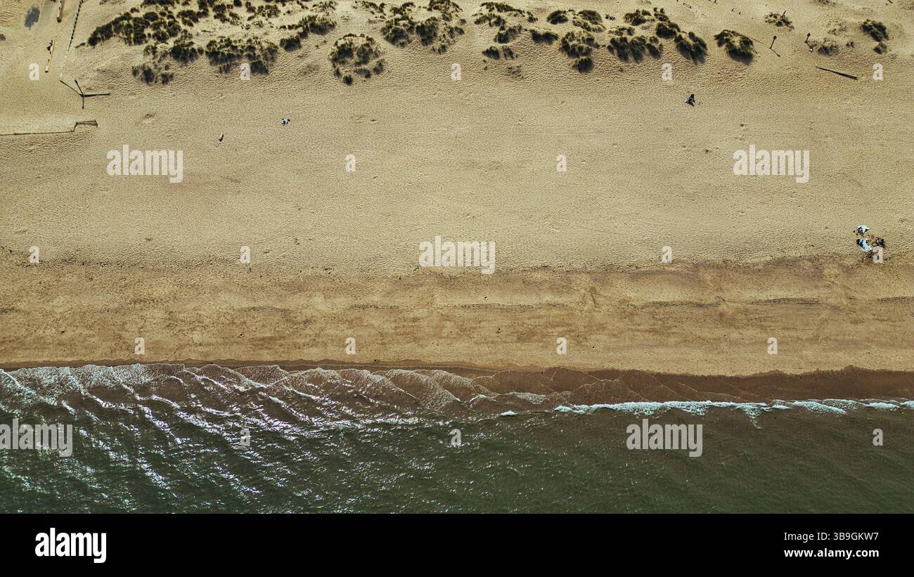 Aerial view of a beach with sand dunes, sparse vegetation, a few people ...