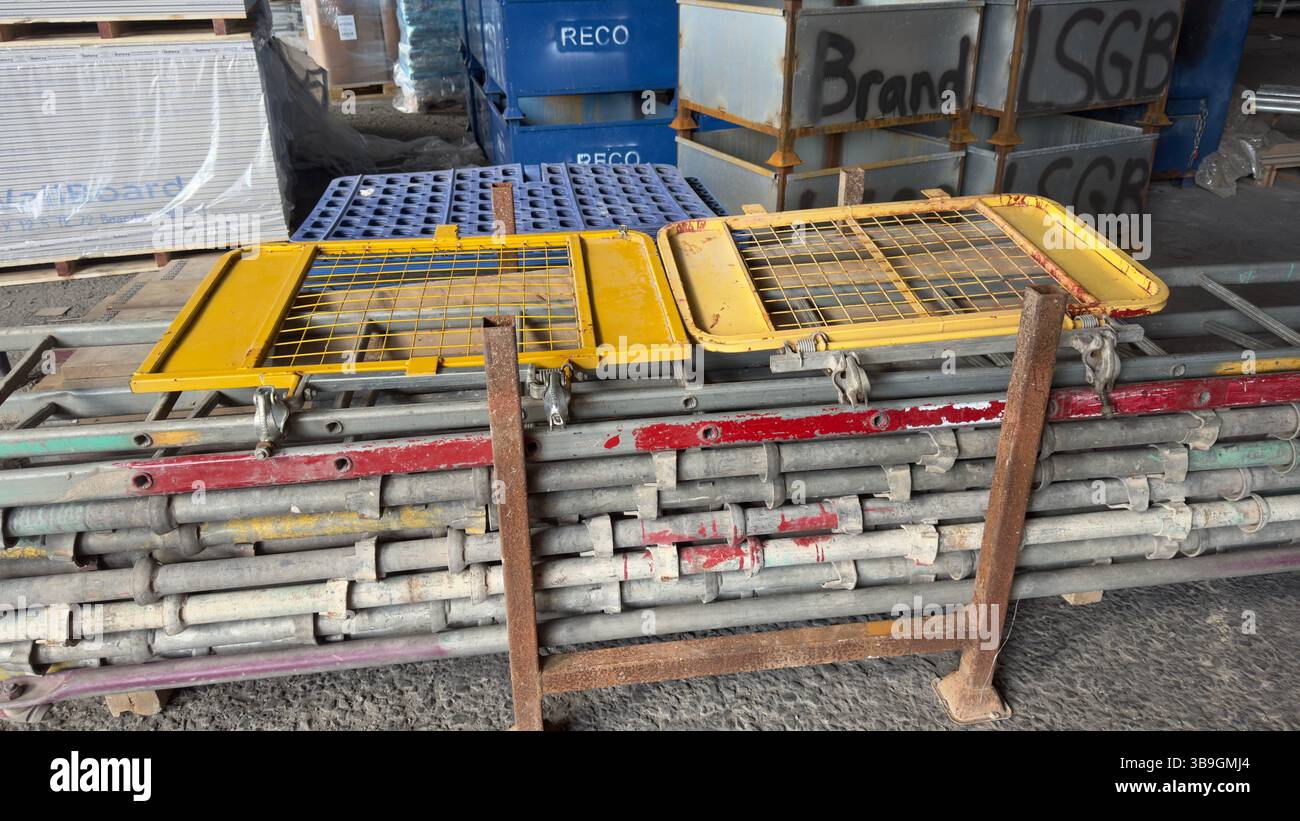 A collection of scaffolding pipes and safety gates are stacked in a ...