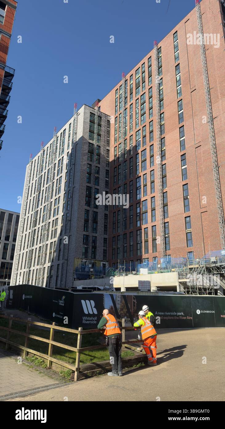 Construction site with high-rise buildings. Three workers in safety ...