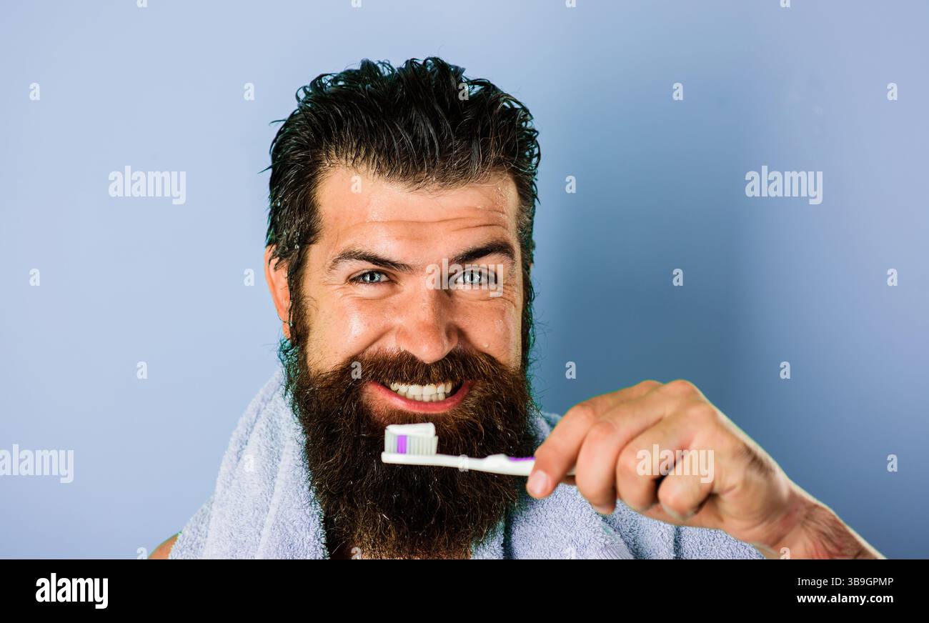 Bearded man brushing teeth in bathroom. Handsome man with toothbrush. Healthy teeth and gums ...