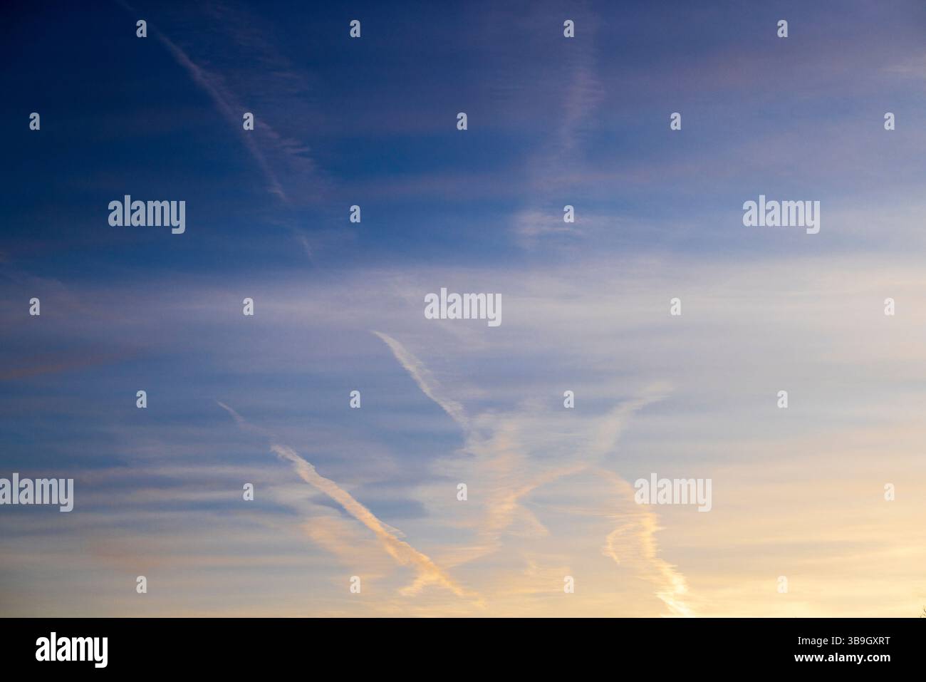 Cirrus clouds ruffled by the wind in the blue sky, contrails of passing ...