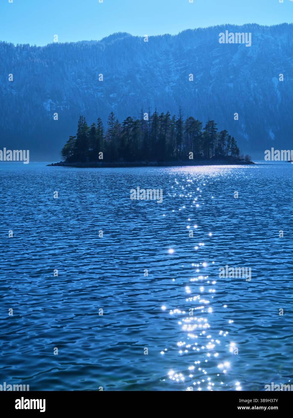 Sparkling water reflects sunlight over a serene island in a mountain ...