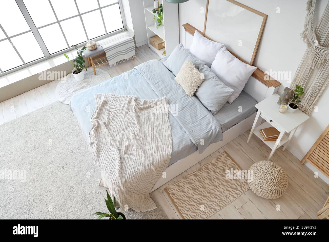 Interior of light bedroom with cozy bed, bedside table, houseplants and ...