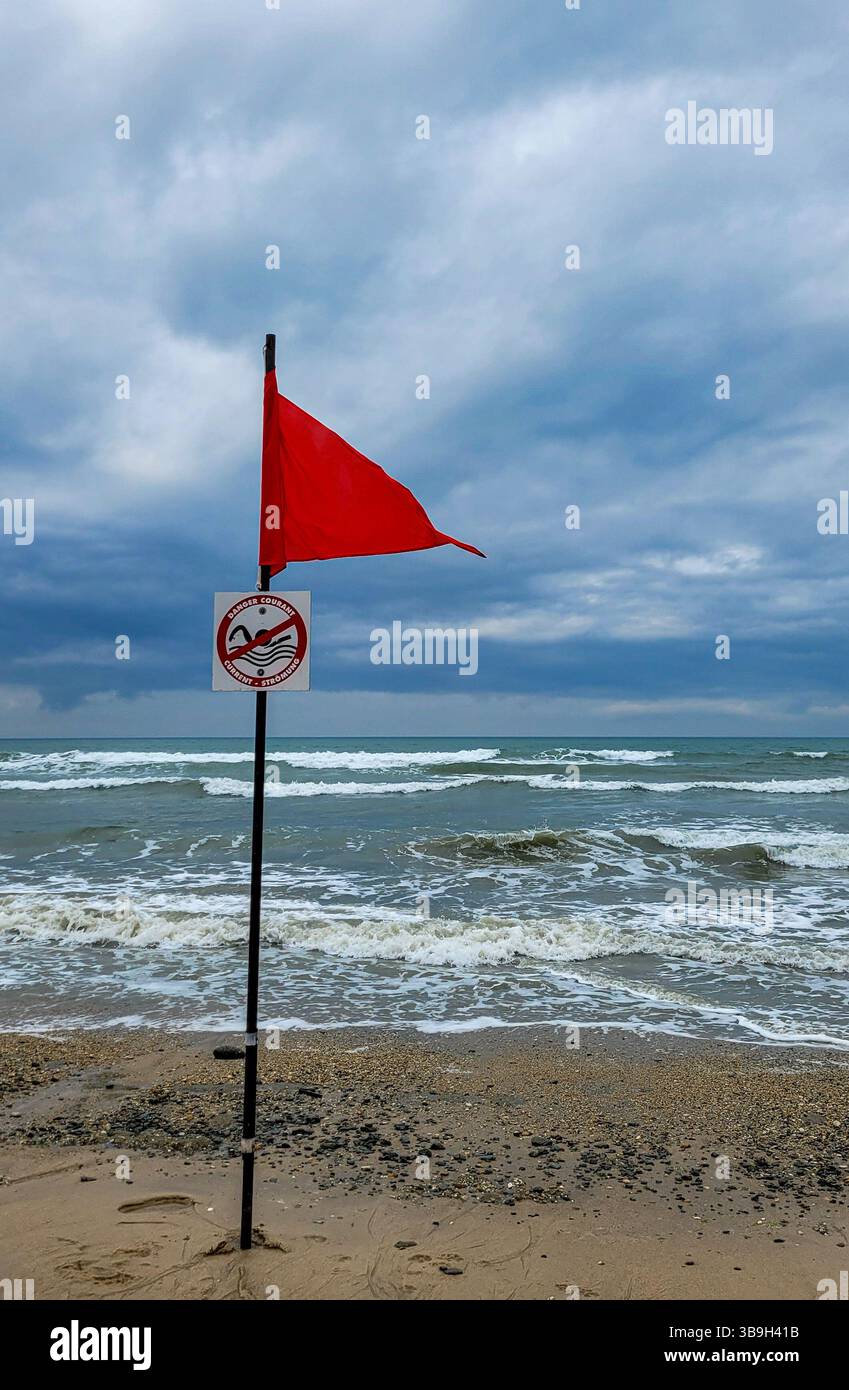Red flag with a sign Prohibiting swimming on a sand beach with ...