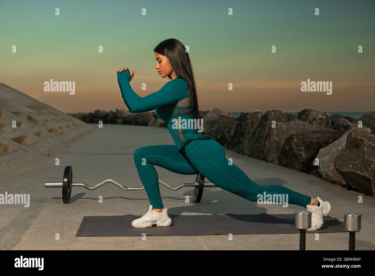 fitness enthusiast in activewear is engaged in lunges on pathway water ...