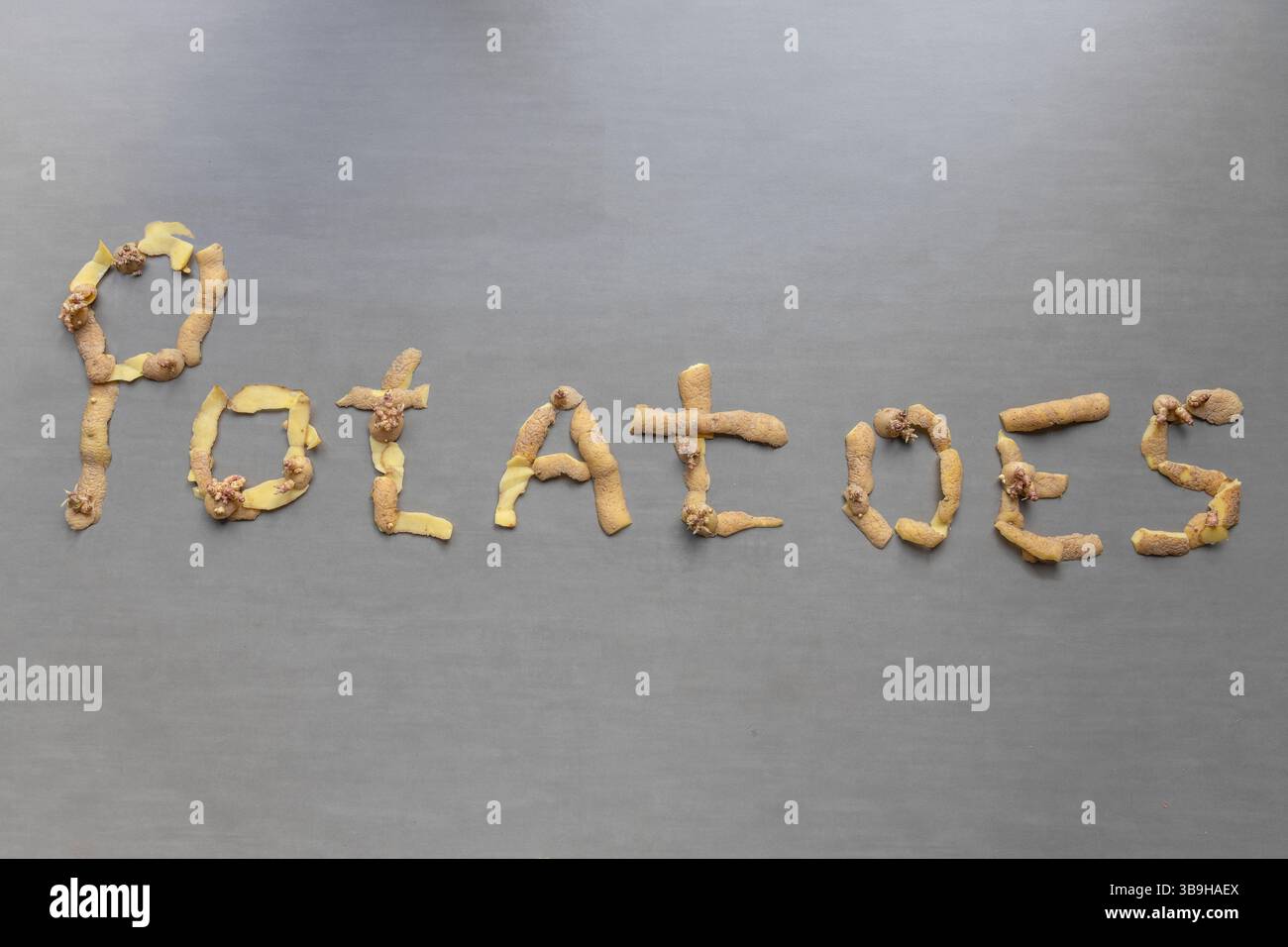 The English word potato is in the form of peels on a gray background on ...