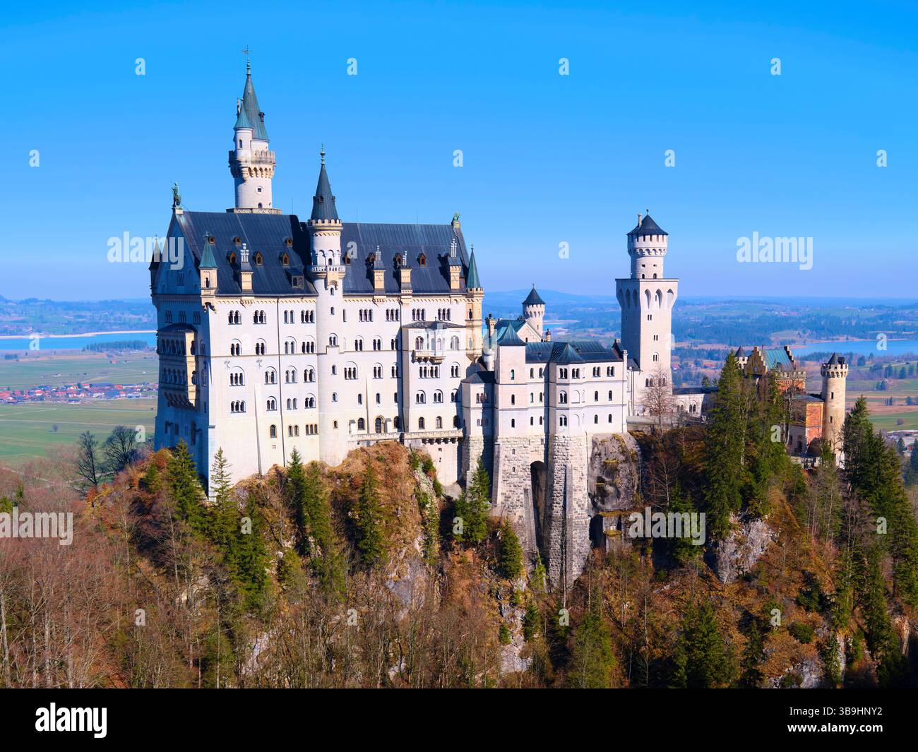Castle nestled atop a hill surrounded by lush greenery and clear blue ...