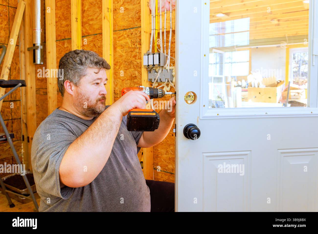 Craftsman carefully attaching doorknob in wooden works filled with ...