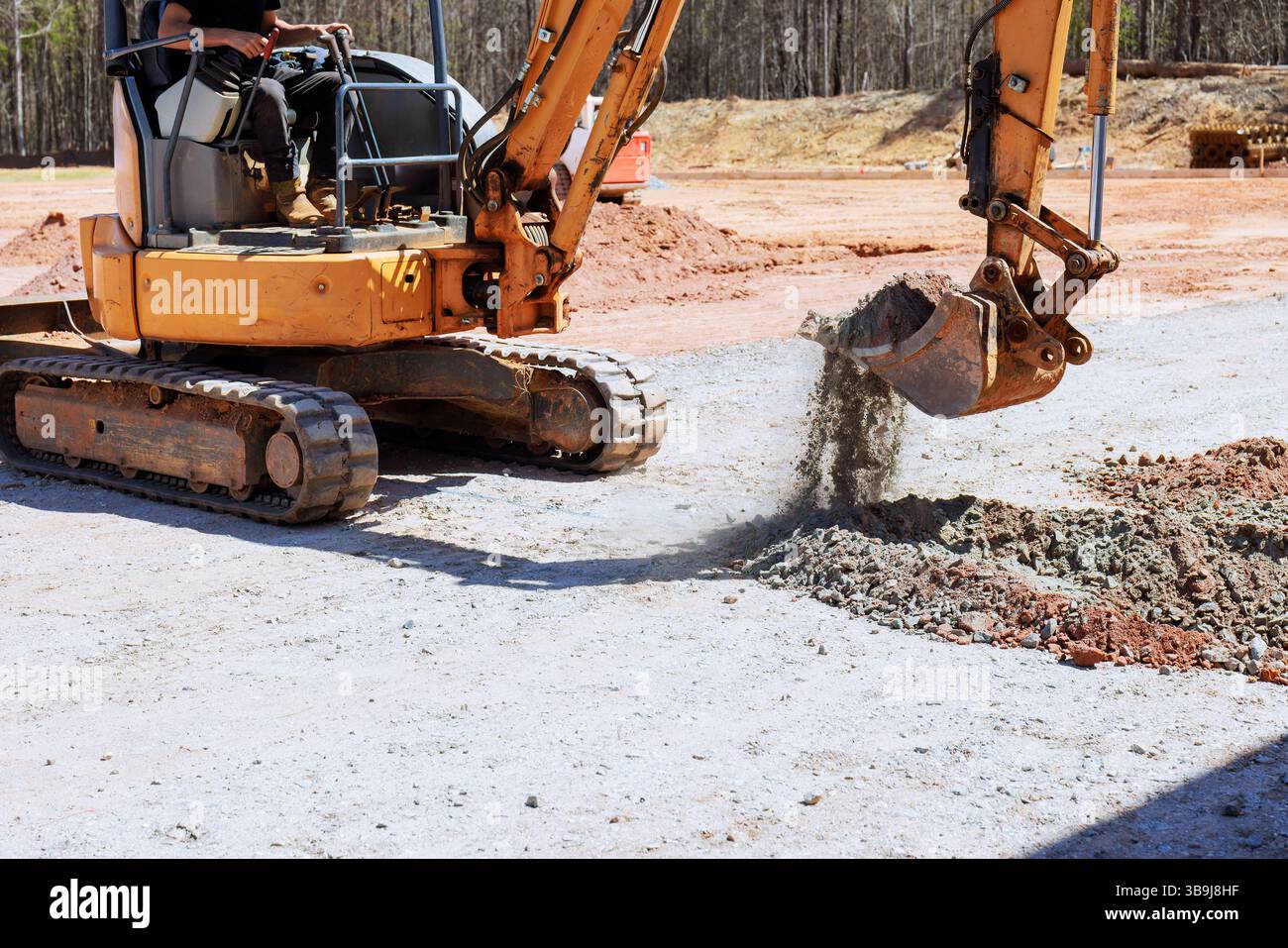 Heavy machinery operator uses an excavator to digs trench, move gravel ...