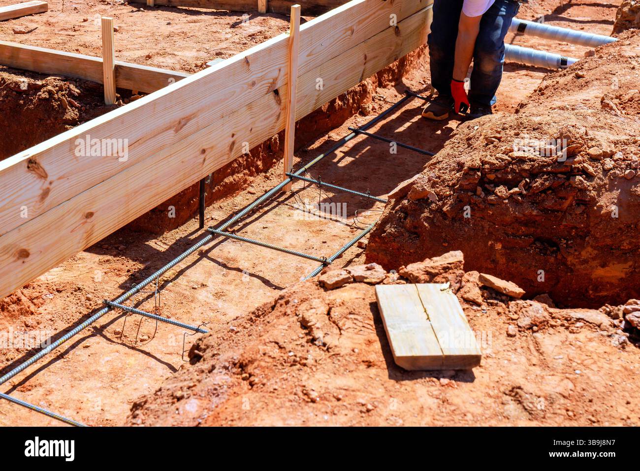Construction worker sets up rebar wooden frames for new foundation on ...