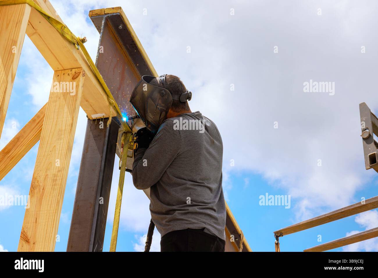 Worker focuses on welding steel beams at construction site during works ...