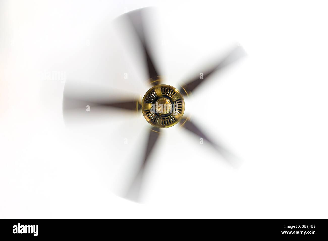 A ceiling fan spinning with visible motion blur on a white ceiling ...