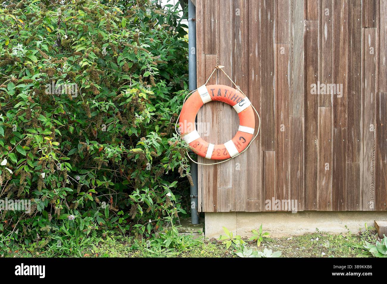 Orange lifebuoy with name of ship or island Tatihou hanging on the wall ...