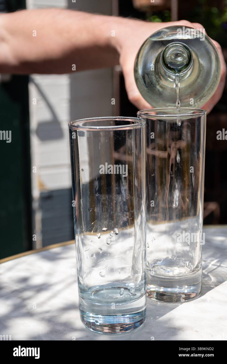 Waiter pouring mineral water from the glass bottle into a glasses, food concept Stock Photo - Alamy