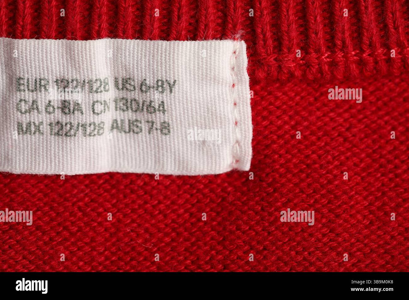 Clothing label on red garment as background, closeup Stock Photo - Alamy