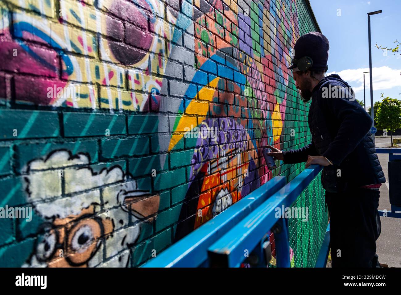 Artist Louis Masai working on a mural for Hit the North Translink ...