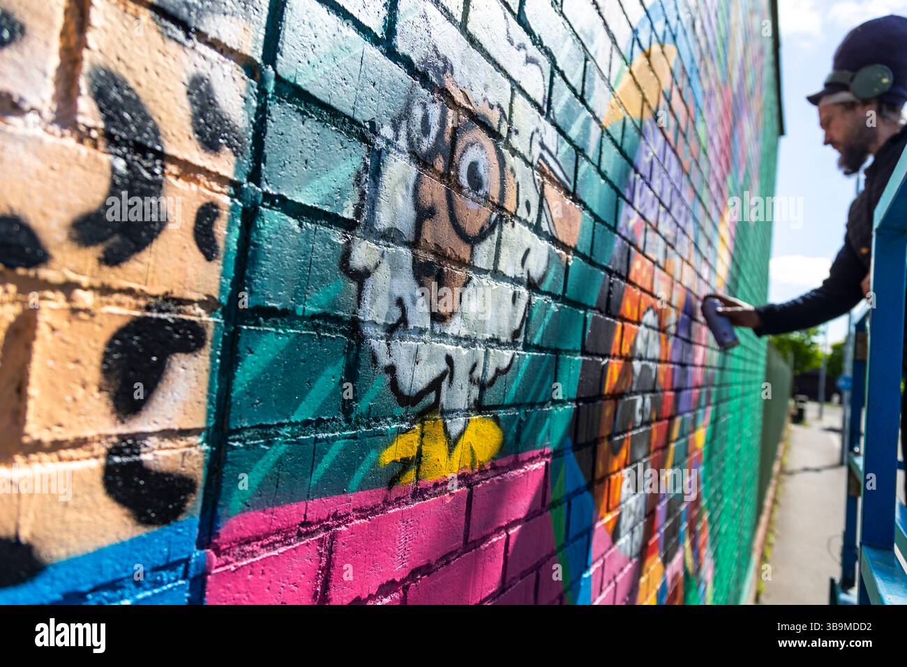 Artist Louis Masai working on a mural for Hit the North Translink ...