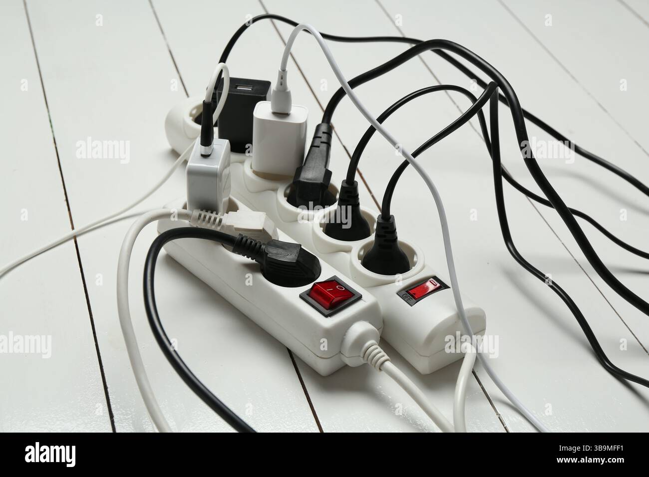 Extension power boards overloaded with plugs on wooden floor Stock ...