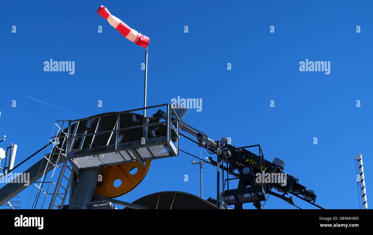 Wind sock indicates wind direction at an industrial site during a clear ...