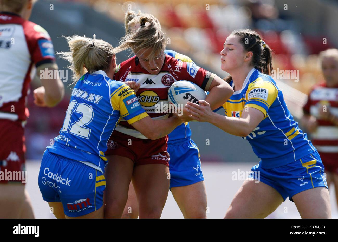 Wigan Warriors' Ellise Deryshire (centre) is tackled by Leeds Rhinos ...