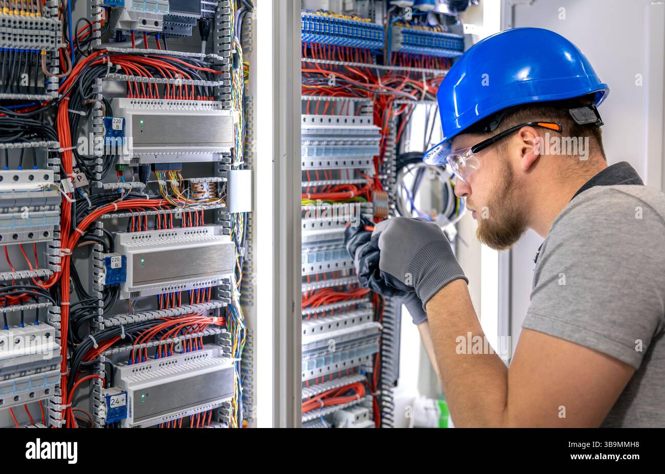 Male electrician in uniform working in a switchboard. Electricity Stock ...