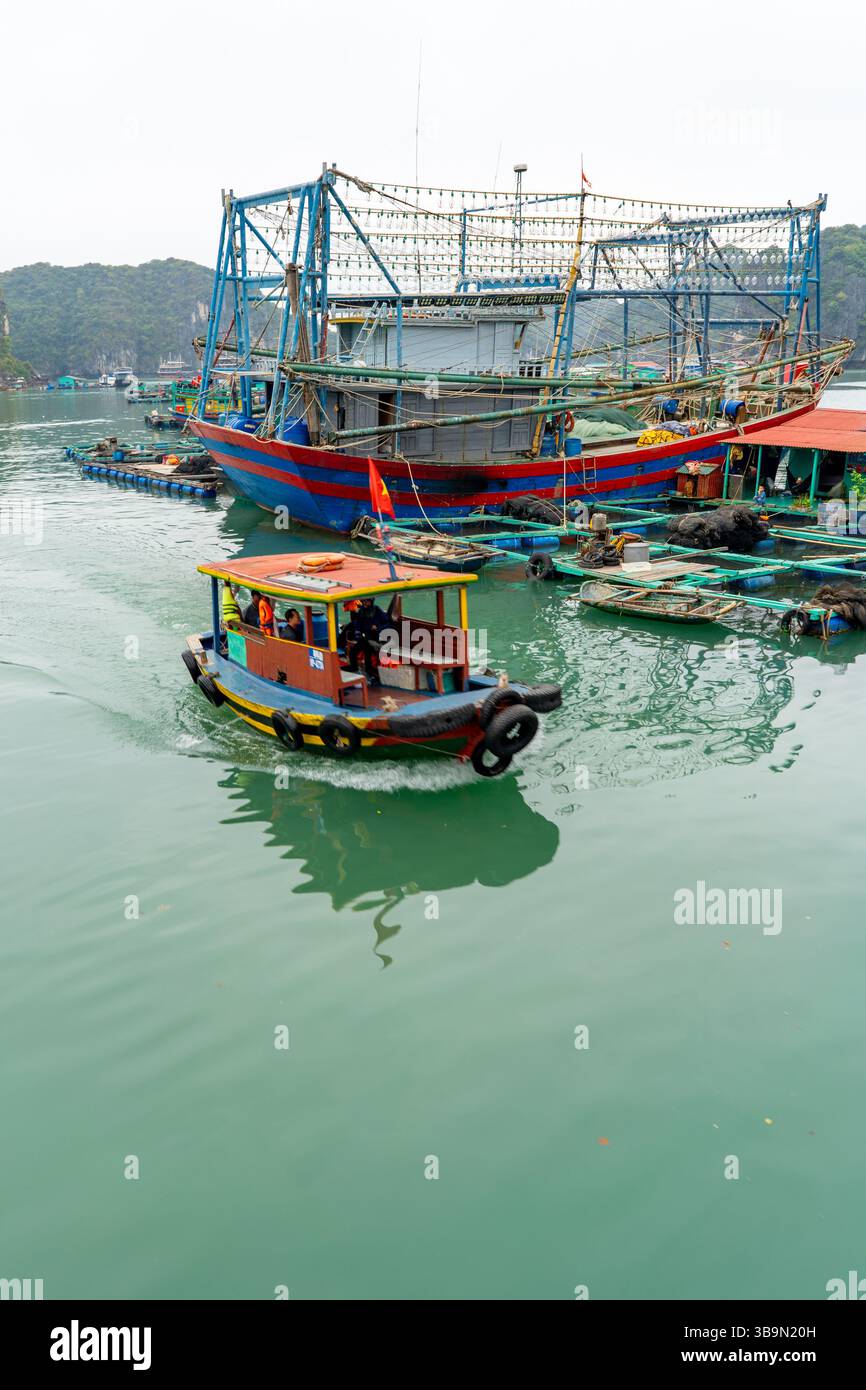 A colorful boat navigates the waters near traditional Vietnamese ...