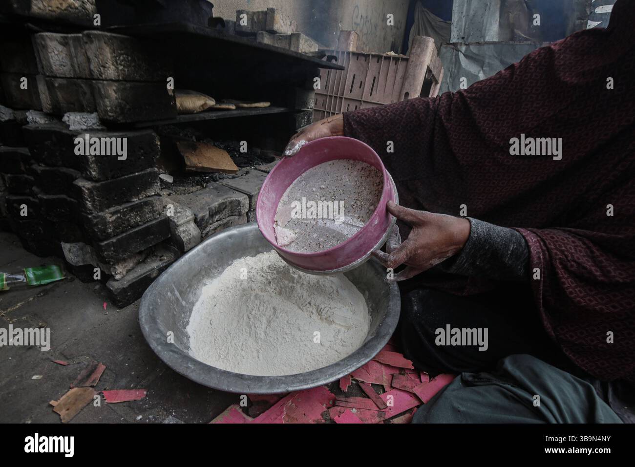 A Palestinian woman prepares bread using stale and spoiled flour as the ...