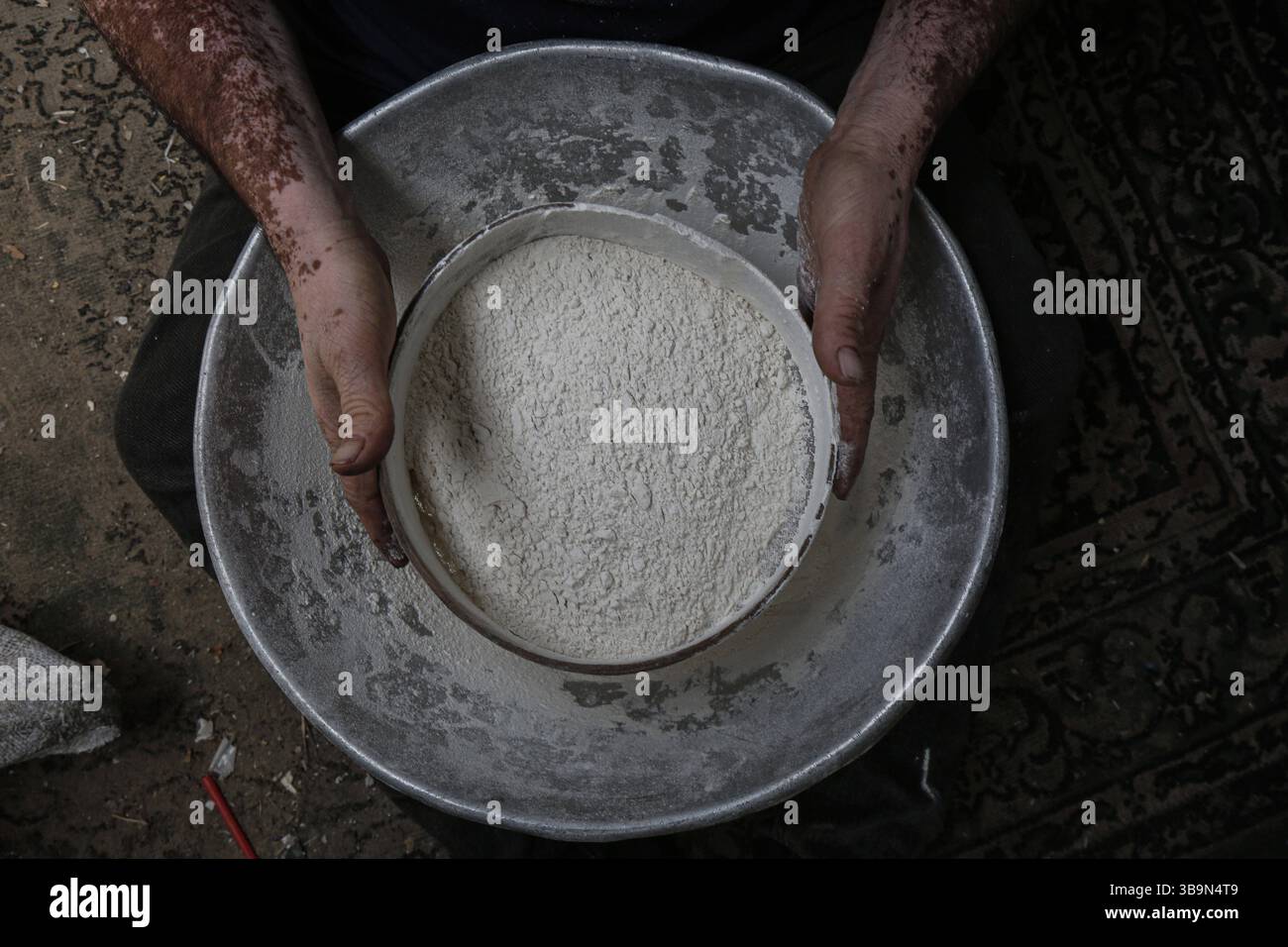 A Palestinian woman prepares bread using stale and spoiled flour as the ...