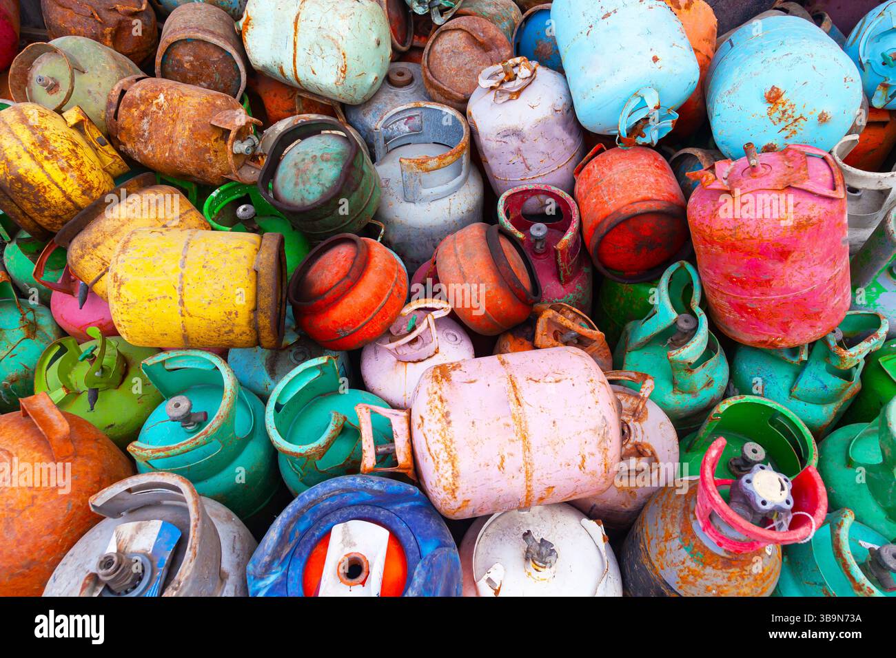 A pile of old used multi-colored gas cylinders of small size. Scrap ...
