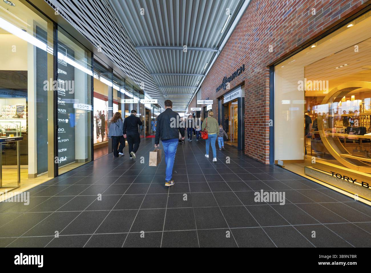 People walking inside a modern, brightly lit shopping centre, Outlet ...