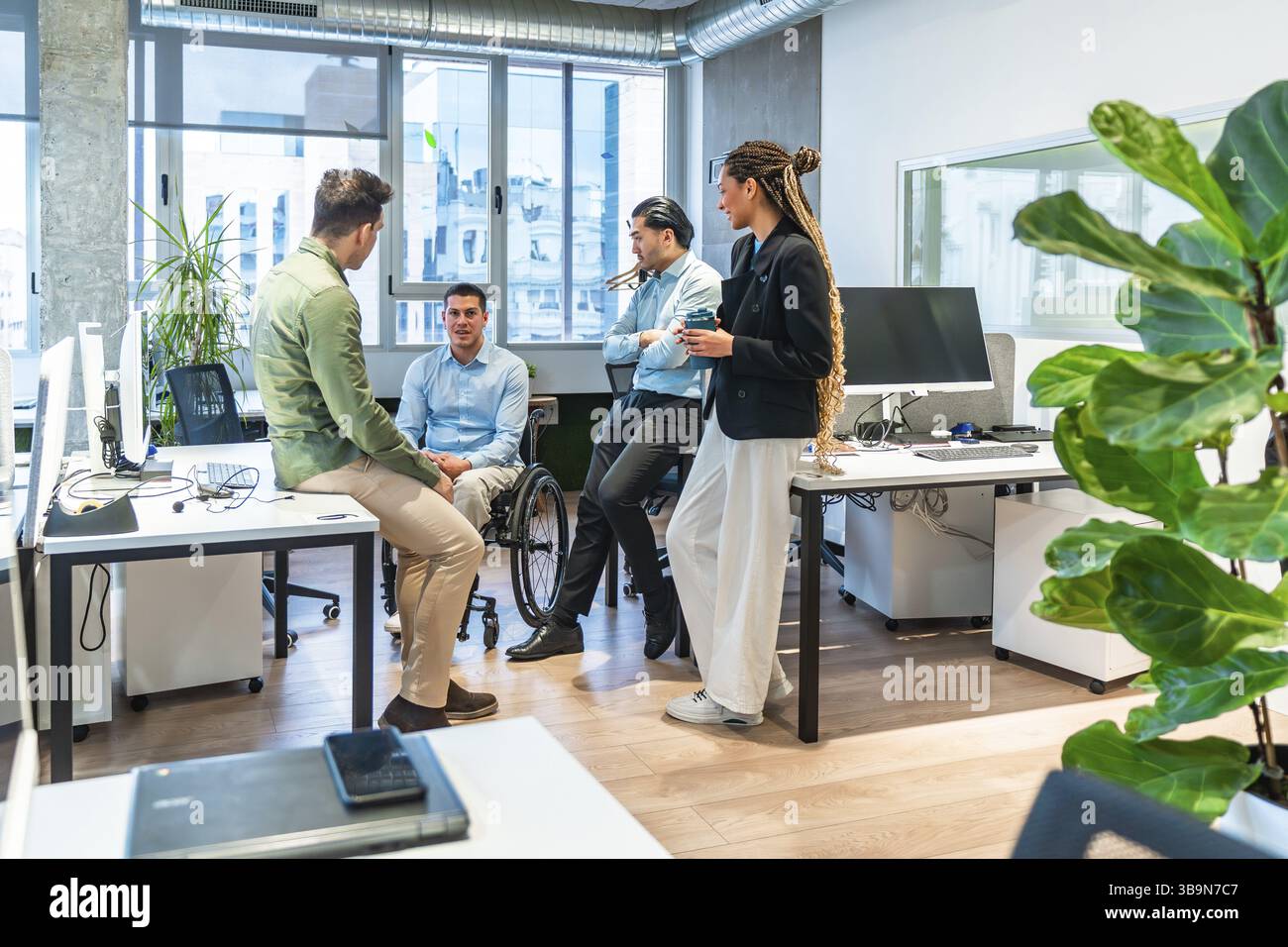 Businesspeople having a conversation in a modern office, one of their ...