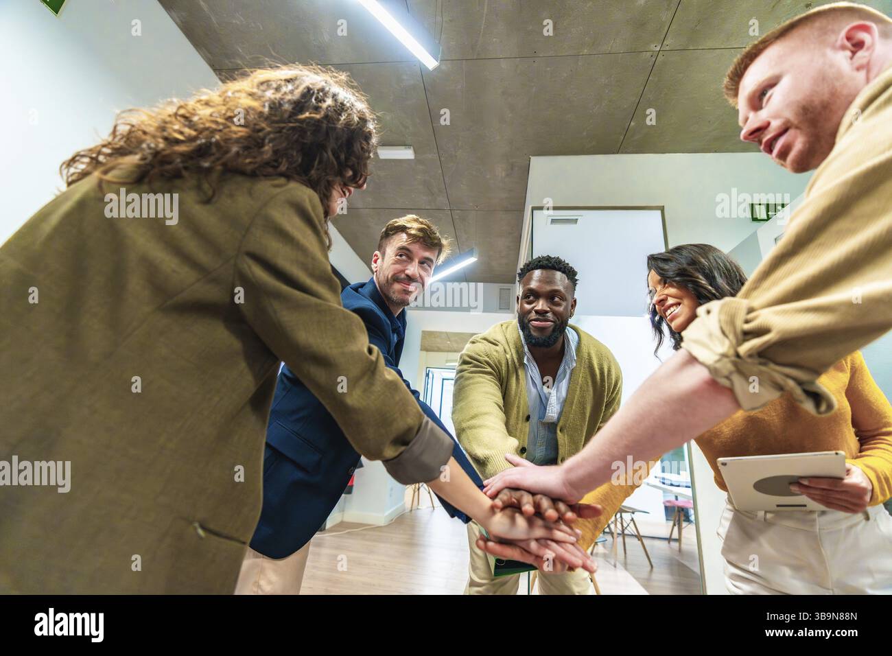 Five businesspeople joining hands together in office, showing their ...