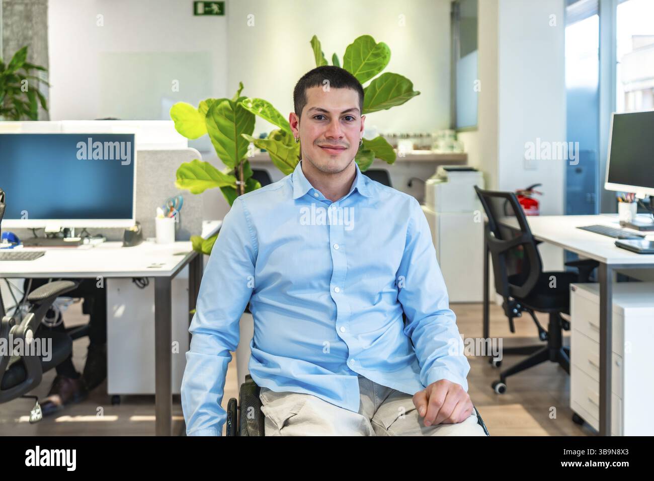 Portrait of a smiling businessman using a wheelchair in a modern office ...