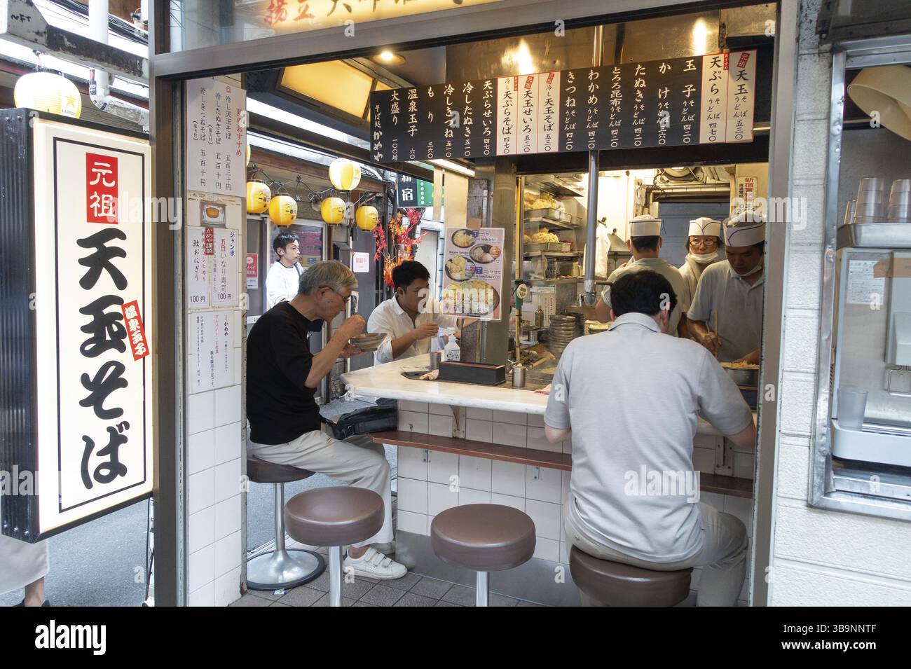 People eating at a street food stall in Memory Lane alley in Omoide ...
