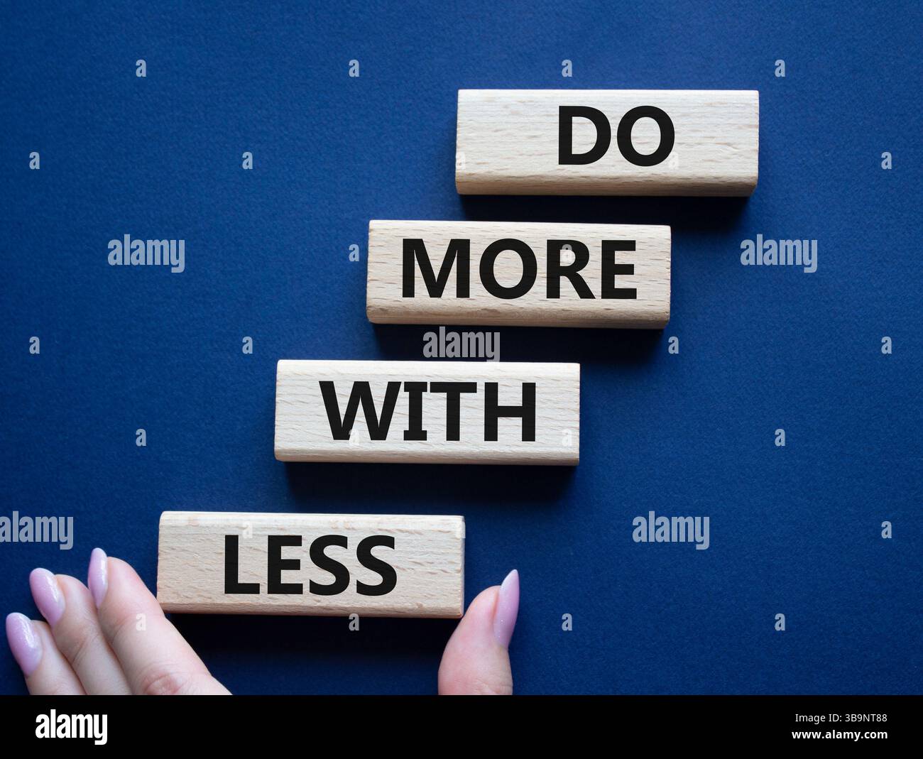 Do more with less symbol. Concept words Do more with less on wooden blocks. Beautiful deep blue ...