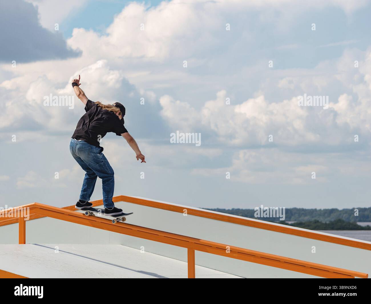 Caucasian Boy doing jump trick through rail on skateboard in skatepark ...