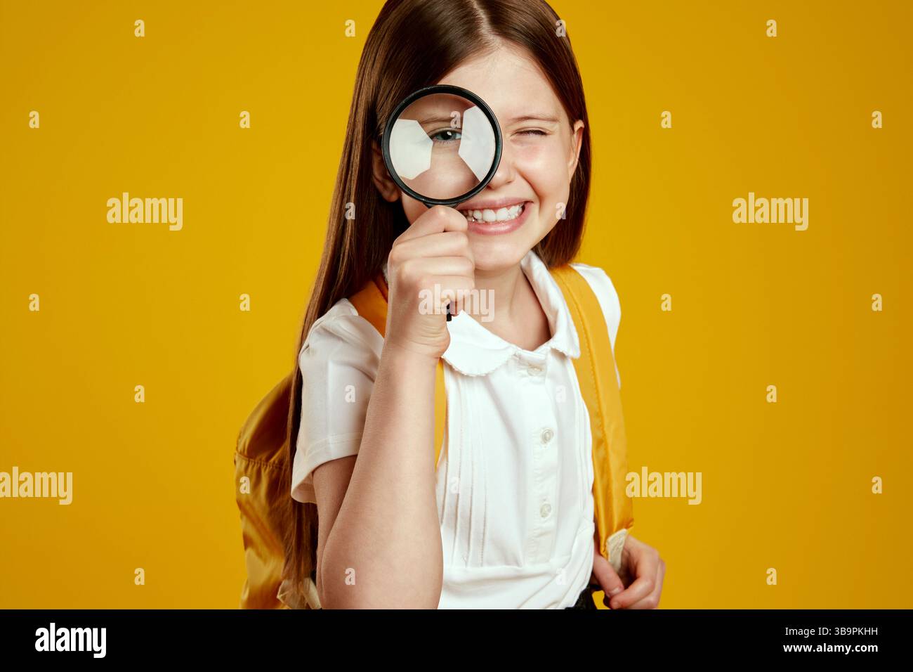 Curious young girl happily exploring with magnifying glass against ...
