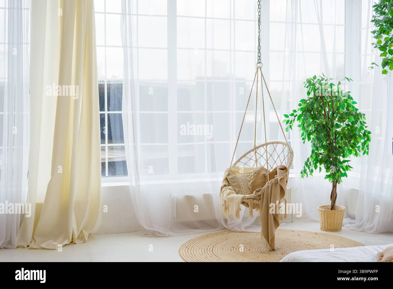 Cozy hanging wicker chair with soft beige plaid in living room with ...