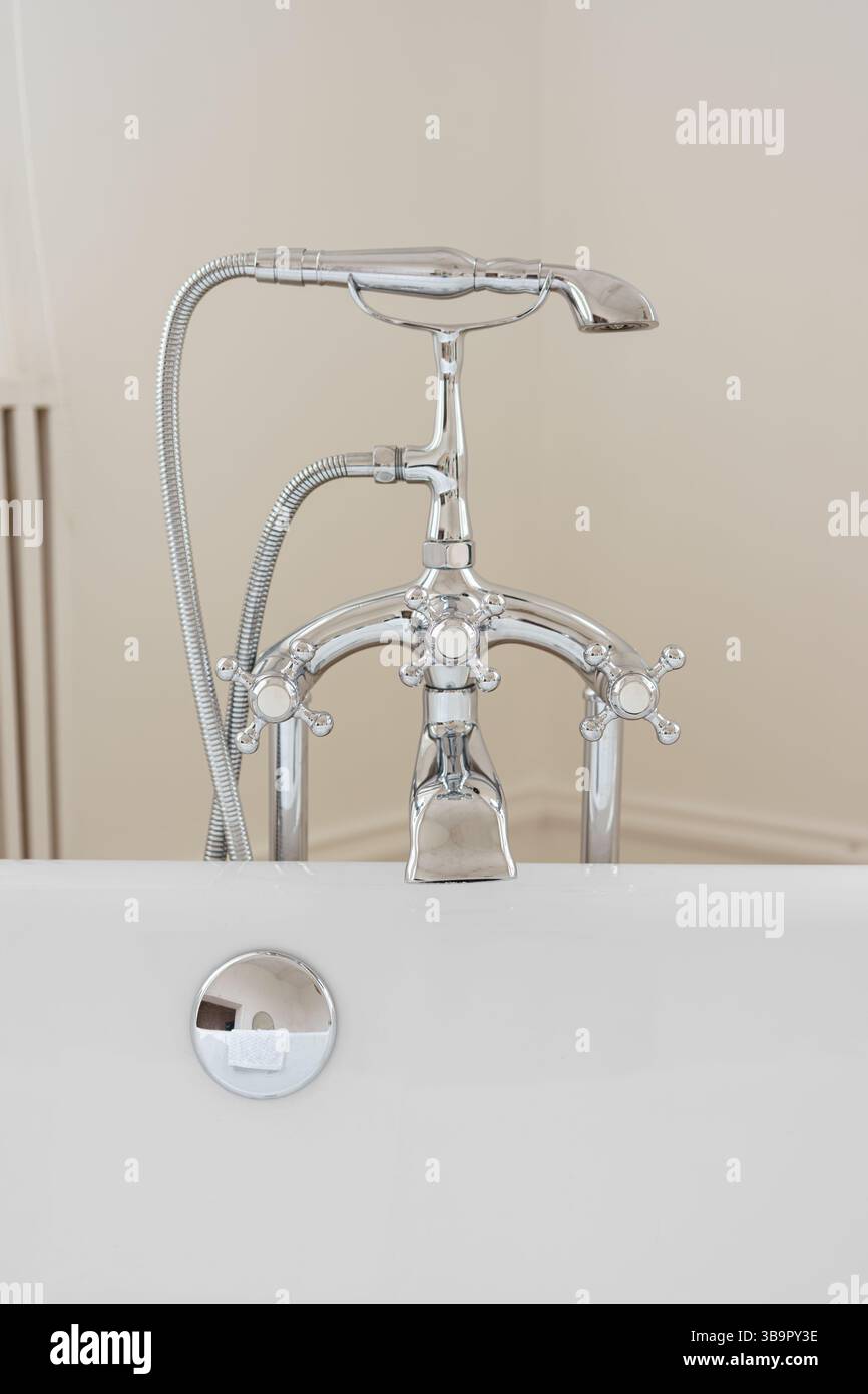 Shiny metal chrome faucet on white freestanding bathtub. Plumbing ...